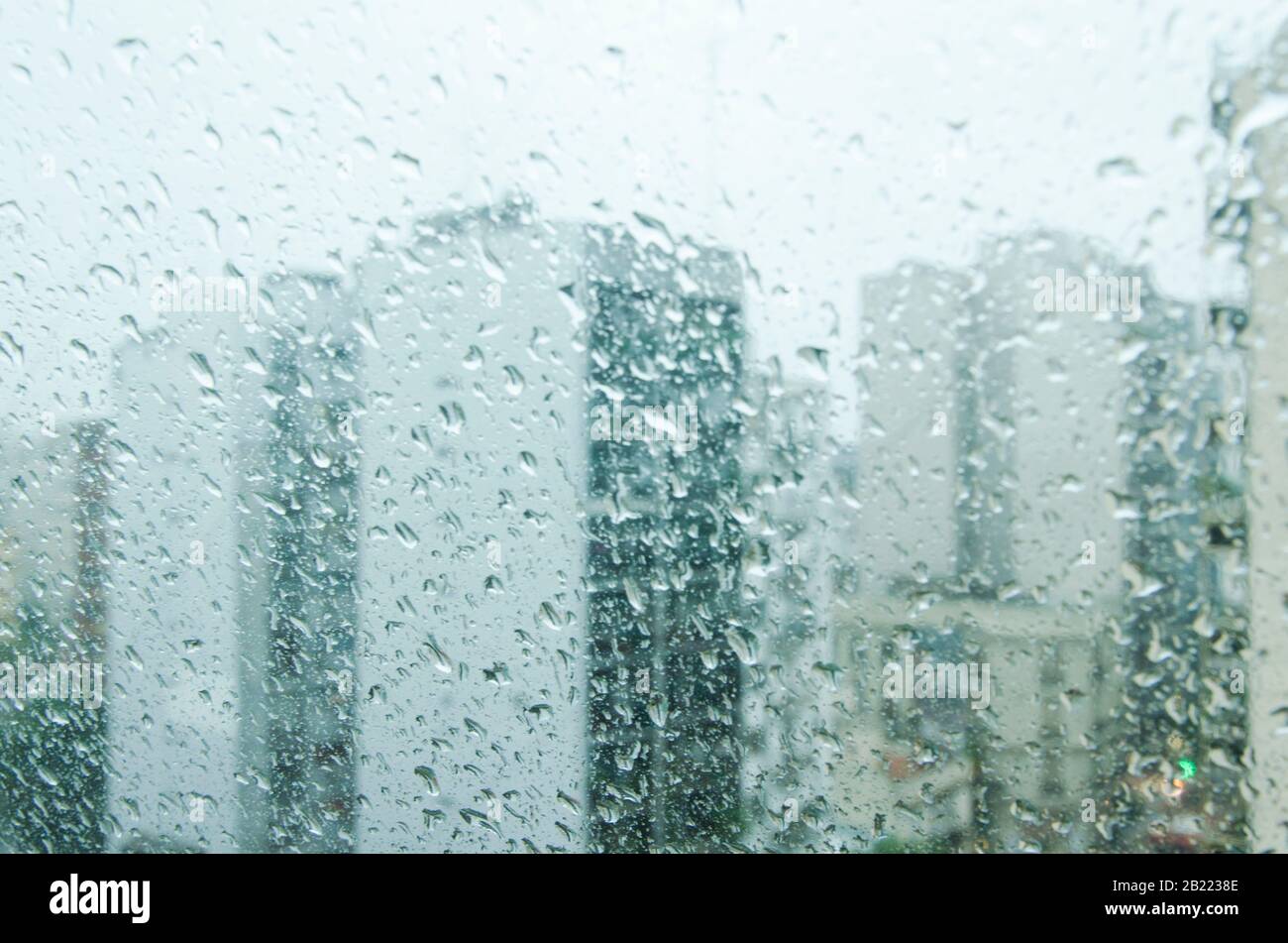 Buildings seen through a glass window full of water droplets a rainy ...