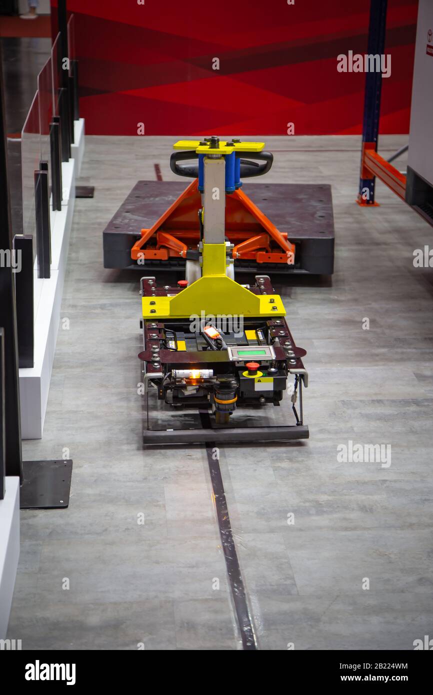 Forked Automatic Guided Vehicles (AGV) handling material in warehouse ... Forked Automatic Guided Vehicles (AGV) handling material in warehouse ...