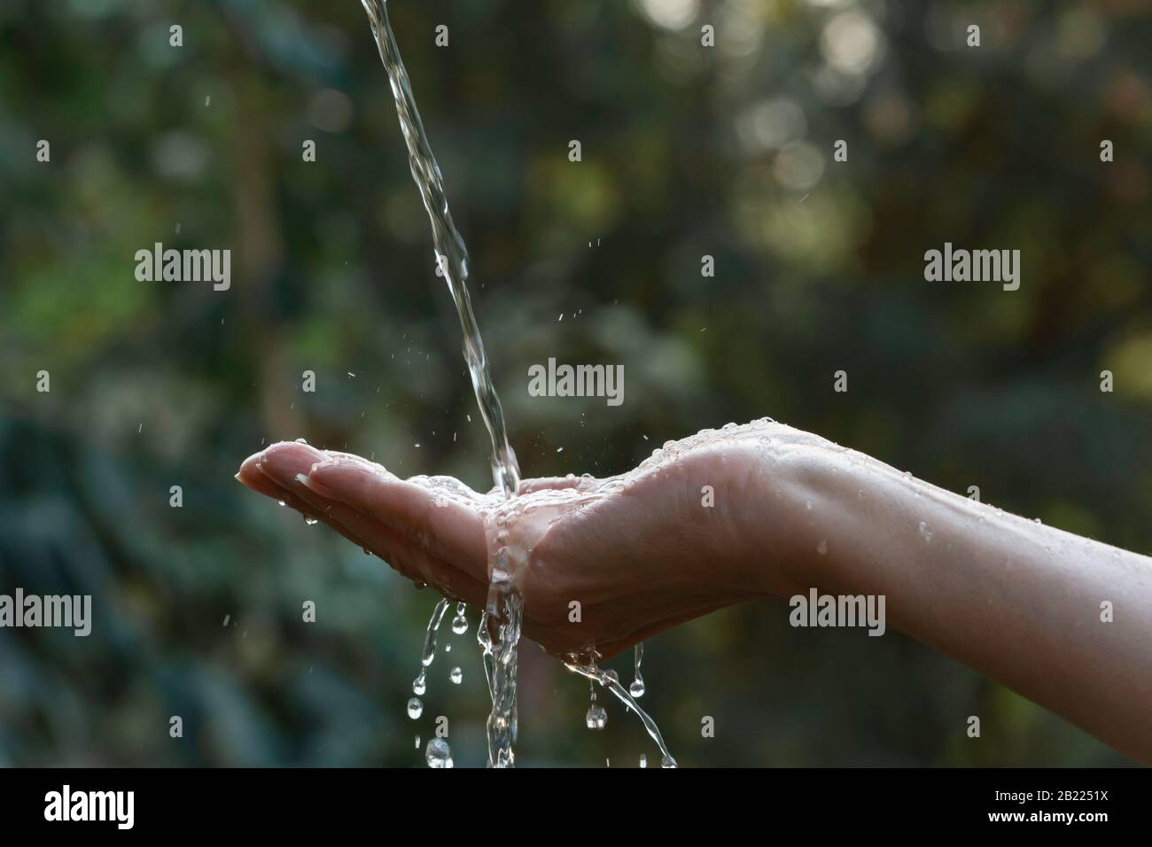 Water pouring on hand with blurred nature background Stock Photo - Alamy