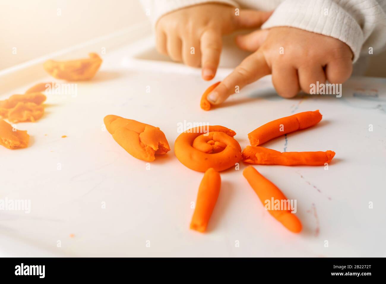 Little toddler plays play dough. Modeling orange sun. Creativity ...