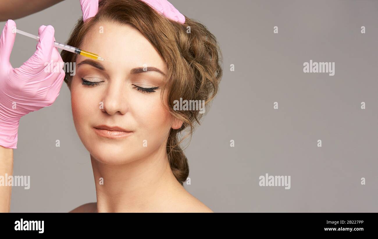Face needle injection. Young woman cosmetology procedure. Doctor pink ...
