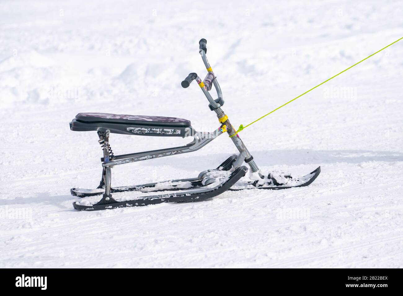 Back view of child in pulling sledge and running up snowy slope while ...
