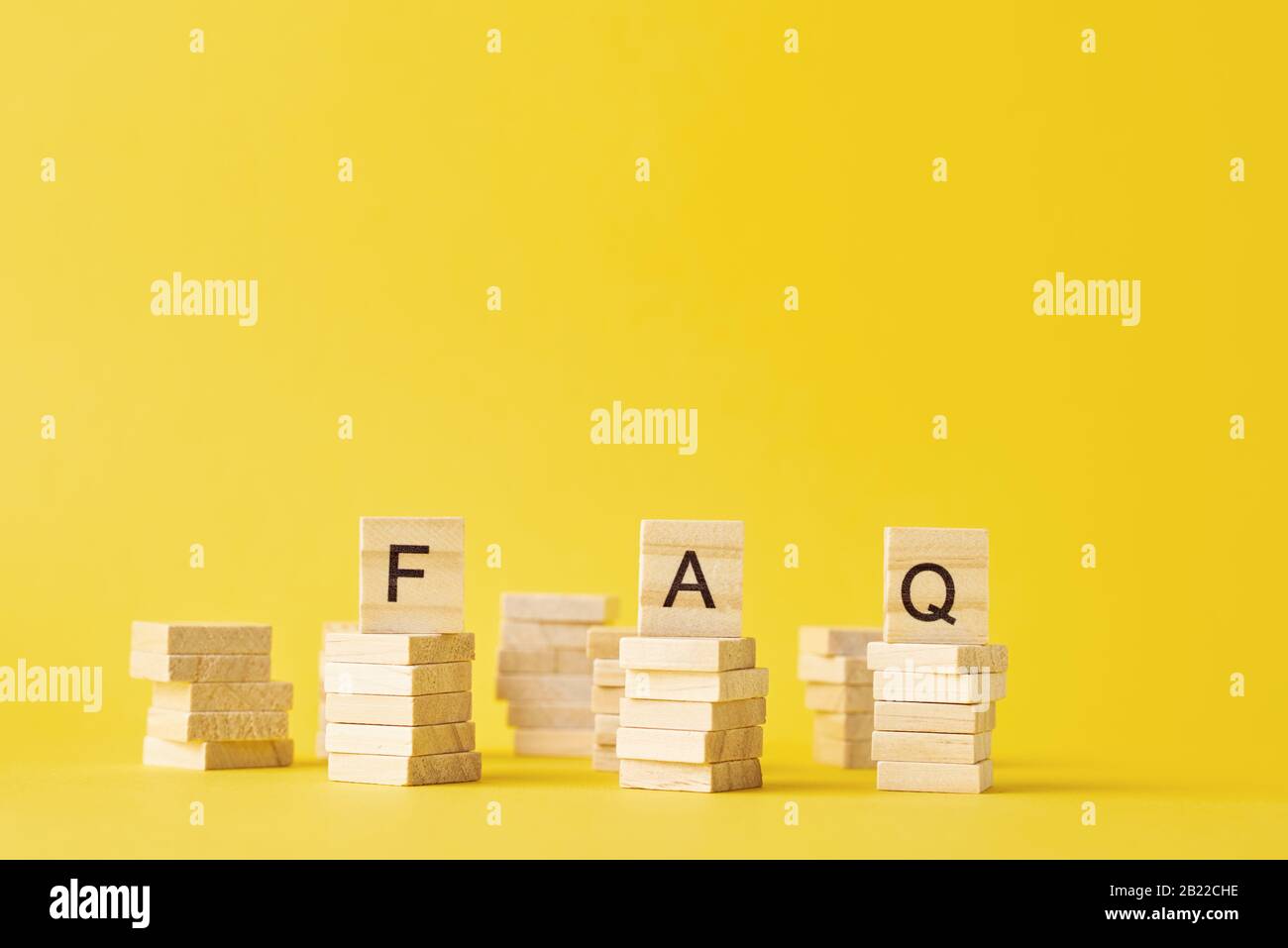 Wooden blocks with word FAQ on yellow baclground. Frequently asked ...
