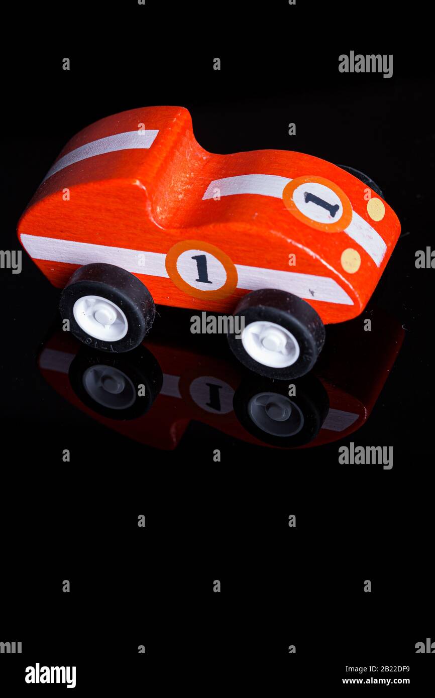 Red toy tiny racing car with number one reflected on a black surface ...