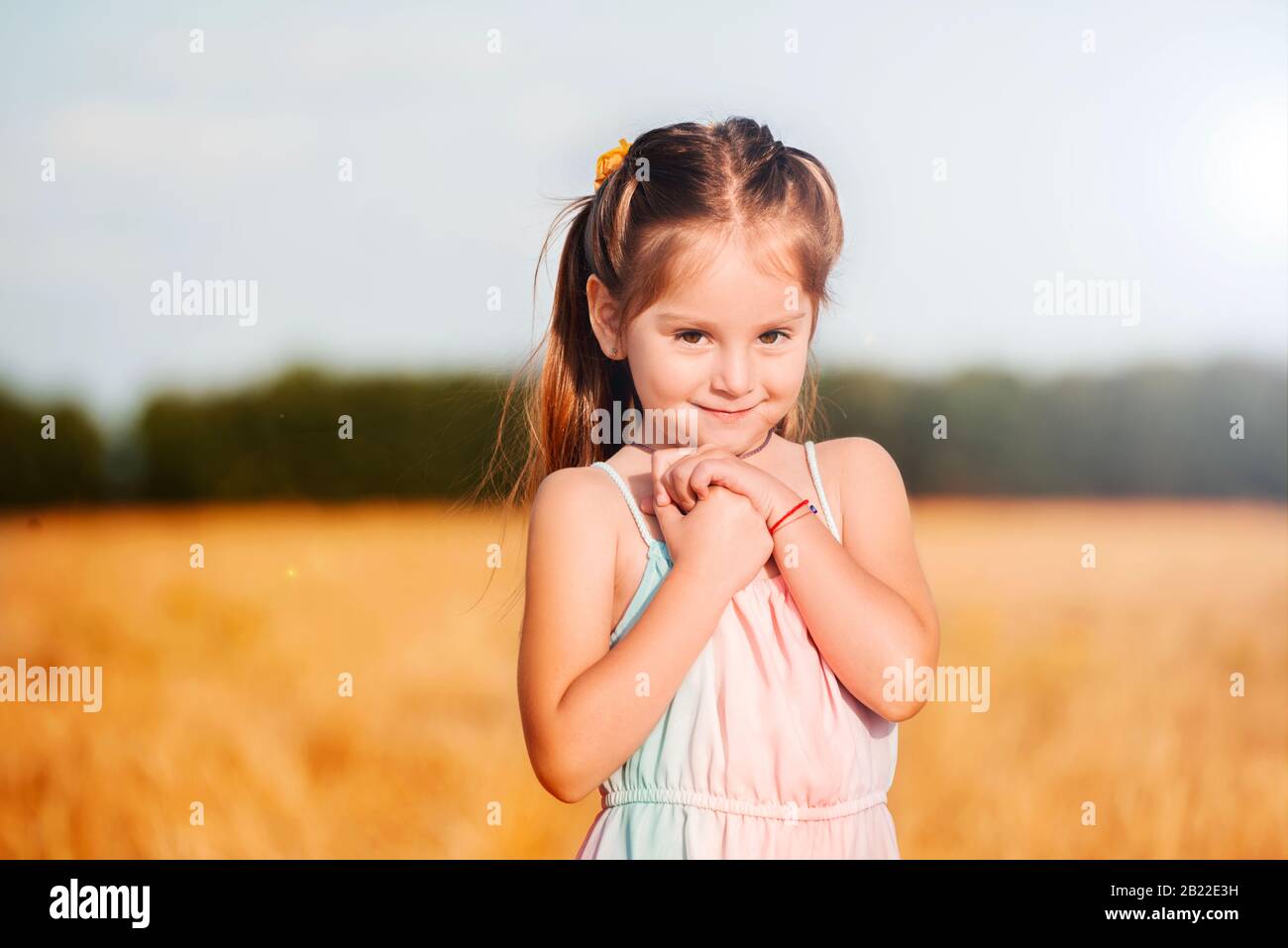 Portrait of a beautiful cute little long-haired girl in a dress posing ...