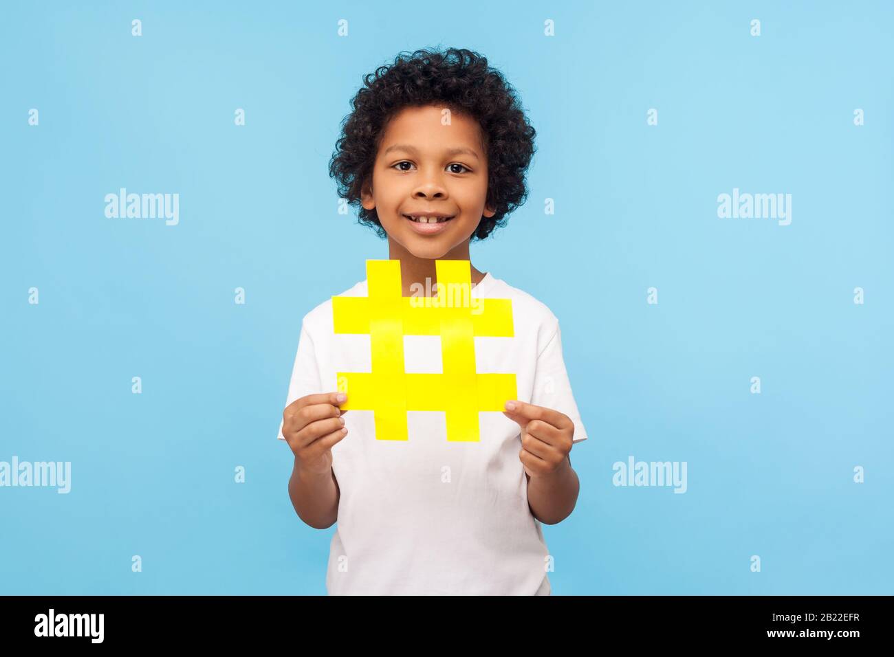 Charming happy cute little boy with curly hair in T-shirt holding big ...