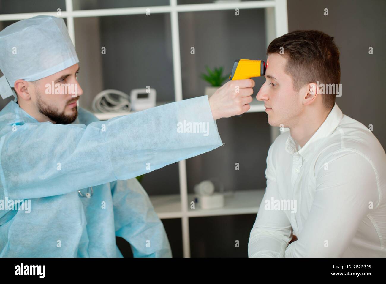 Doctor measures the patient's temperature with a laser thermometer ...