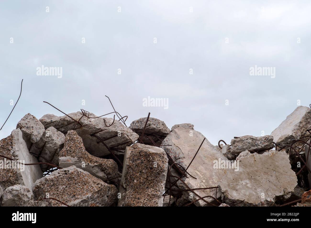A pile of large gray concrete fragments with protruding fittings ...