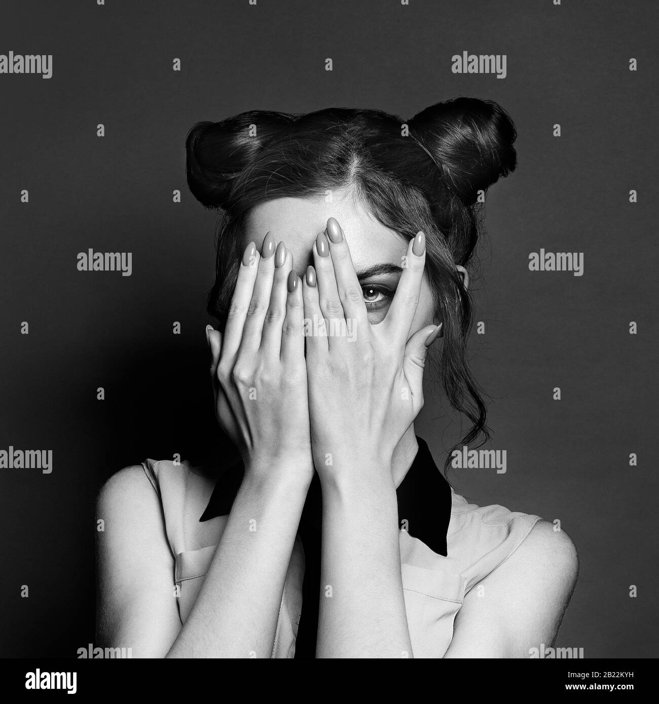 Black and white portrait of young woman hiding behind her hands and ...