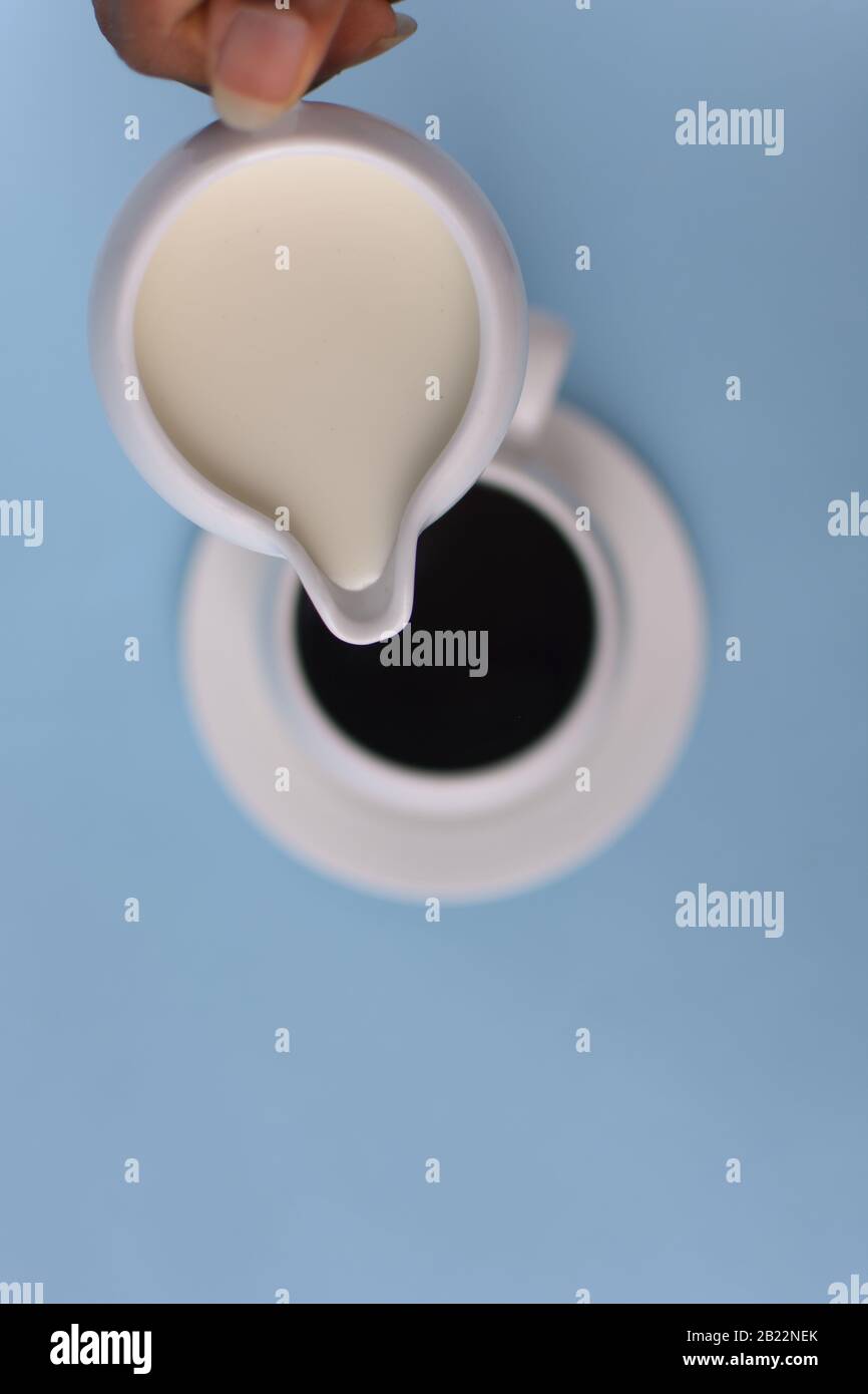 Pouring milk from small ceramic pitcher into a cup of coffee Stock ...