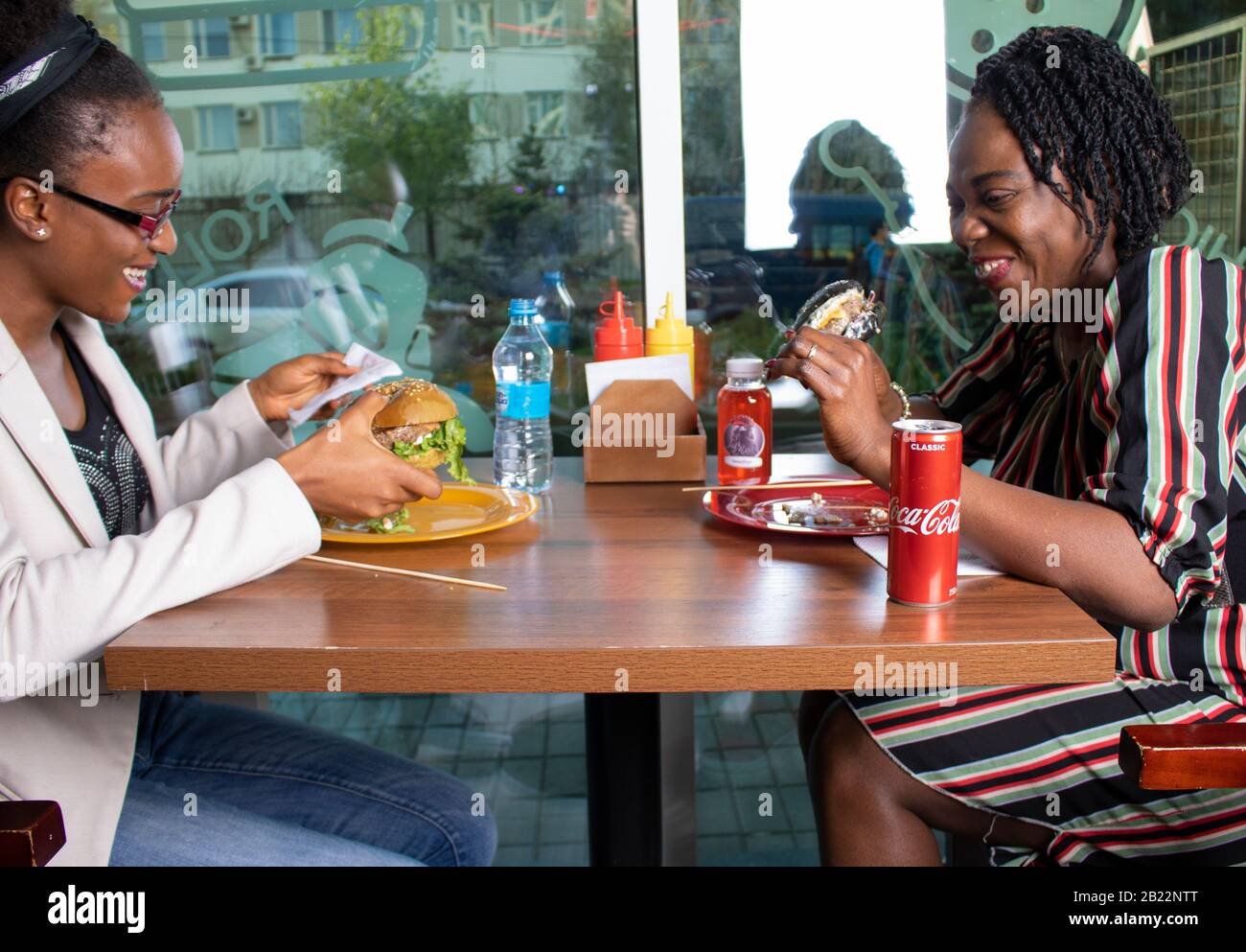 Two beautiful girls talking and eating pizza while having fun together ...