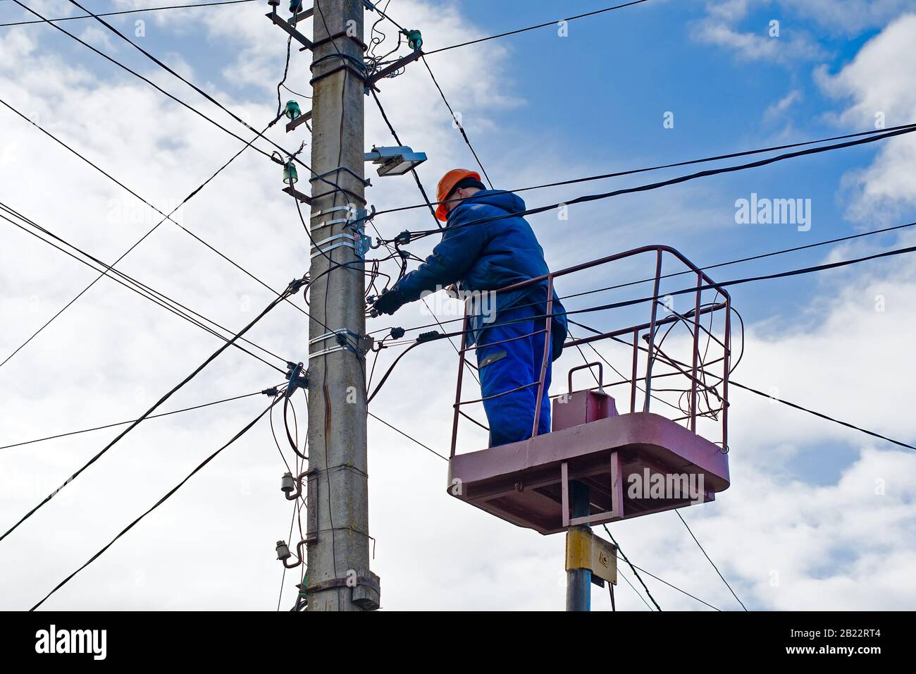 electrician in a helmet and blue suit replaces cable. A electrician ...