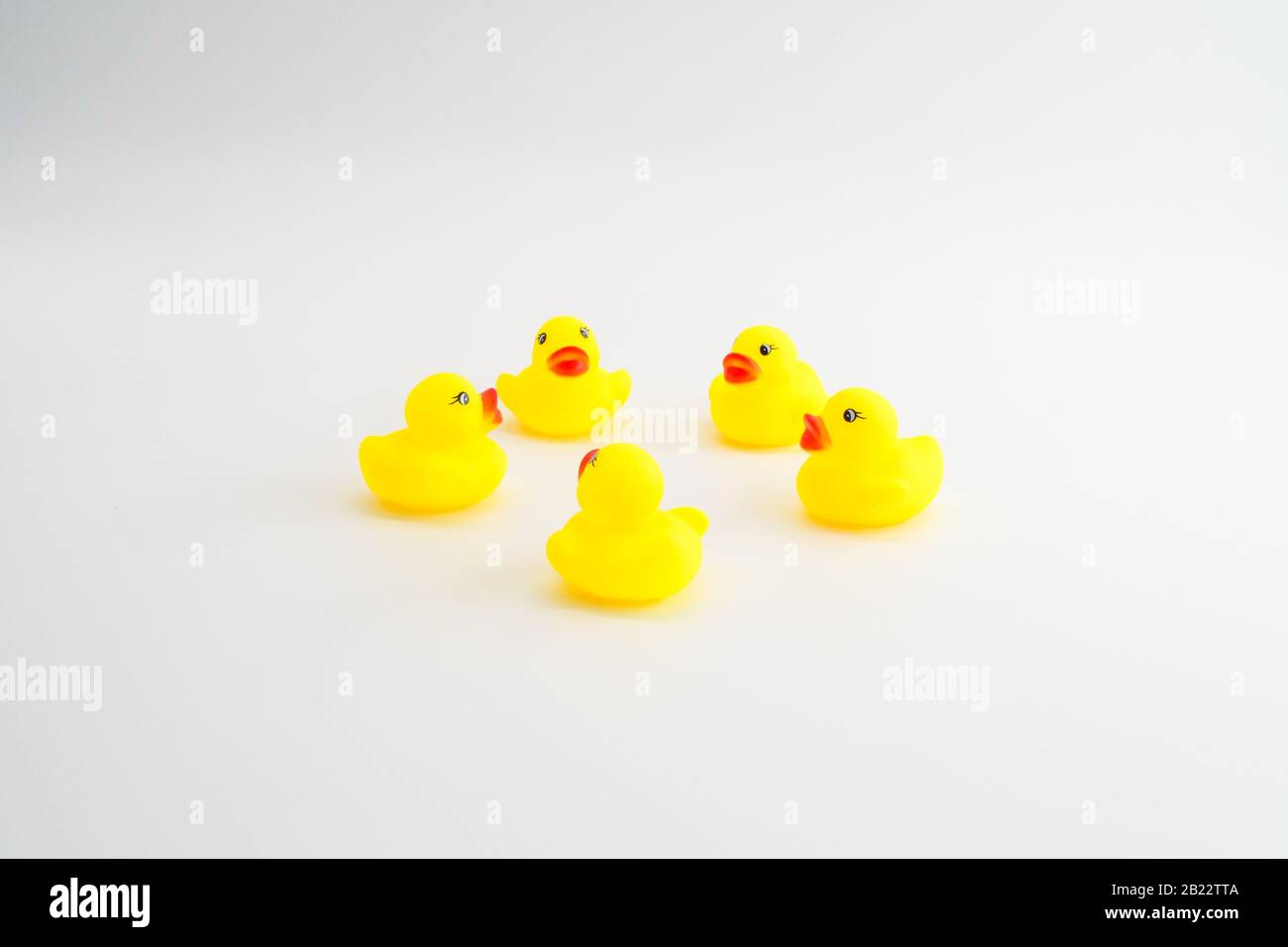 Five mini yellow rubber ducks in circle facing each other. Isolated on ...