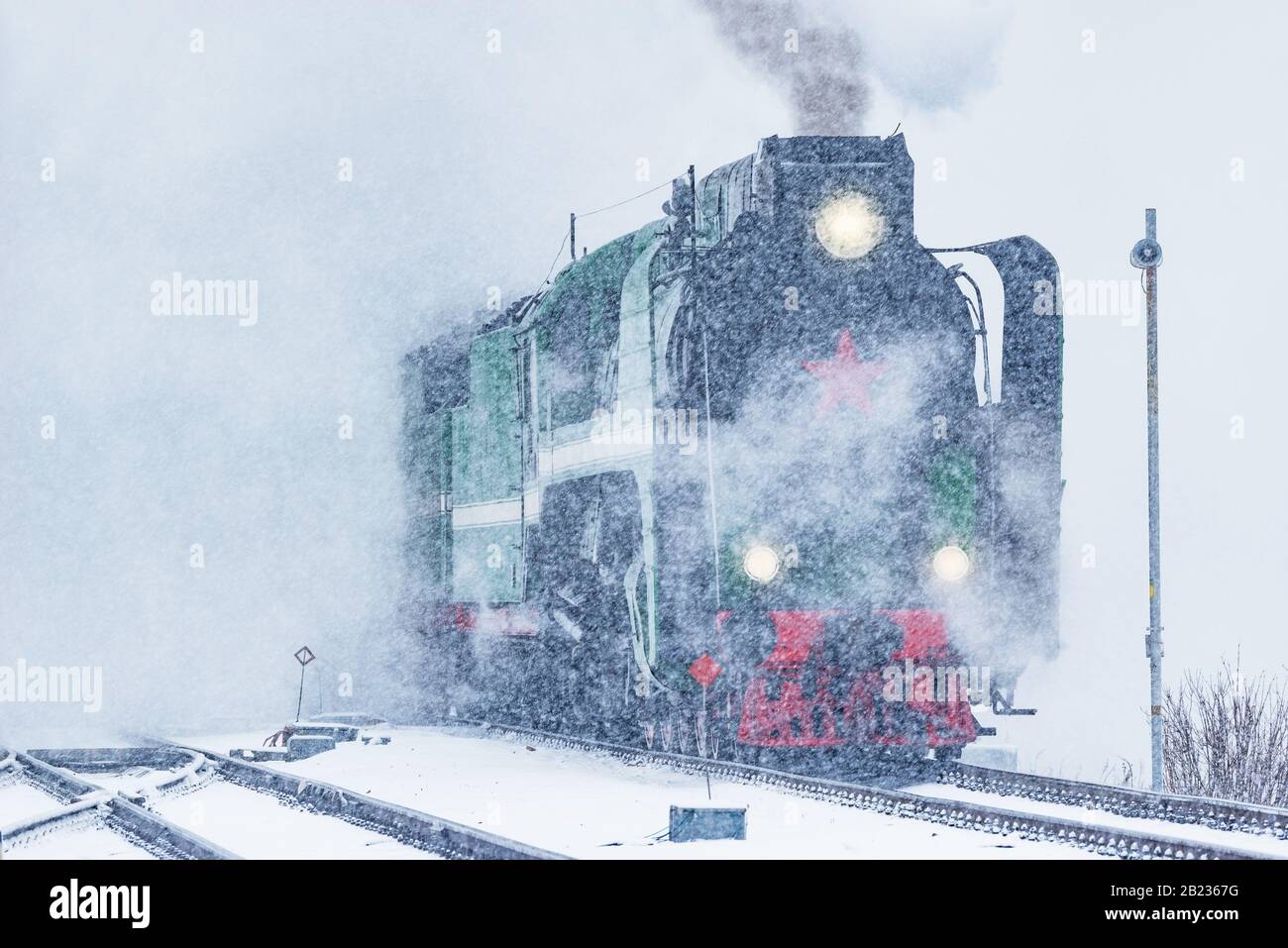 Retro steam train departs from the railway station at winter snowy time ...
