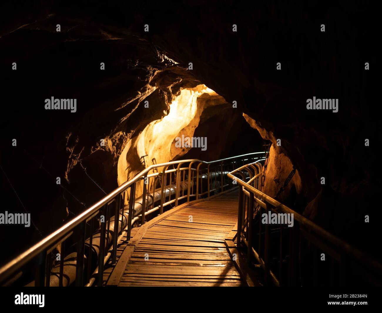 A walkway bridge through dark with single source of light Stock Photo ...