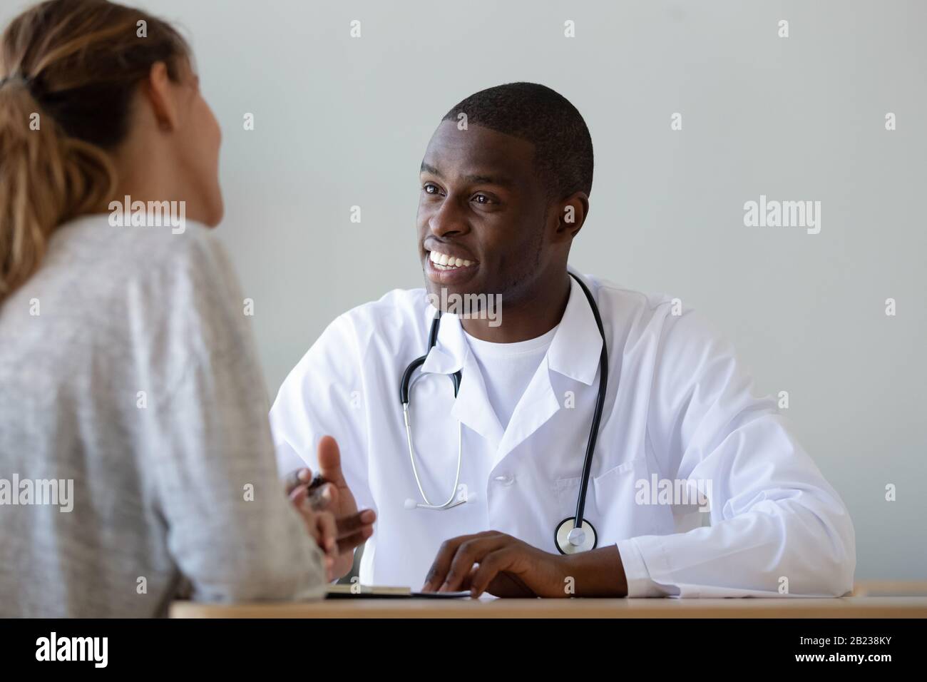 Smiling African American doctor talking to patient at visit Stock Photo ...