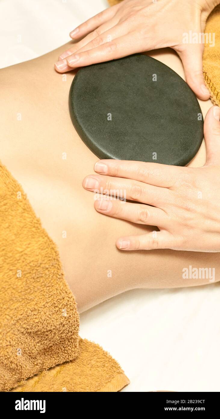body stone massage. Hot rock masseur. Girl at salon with doctor hands ...
