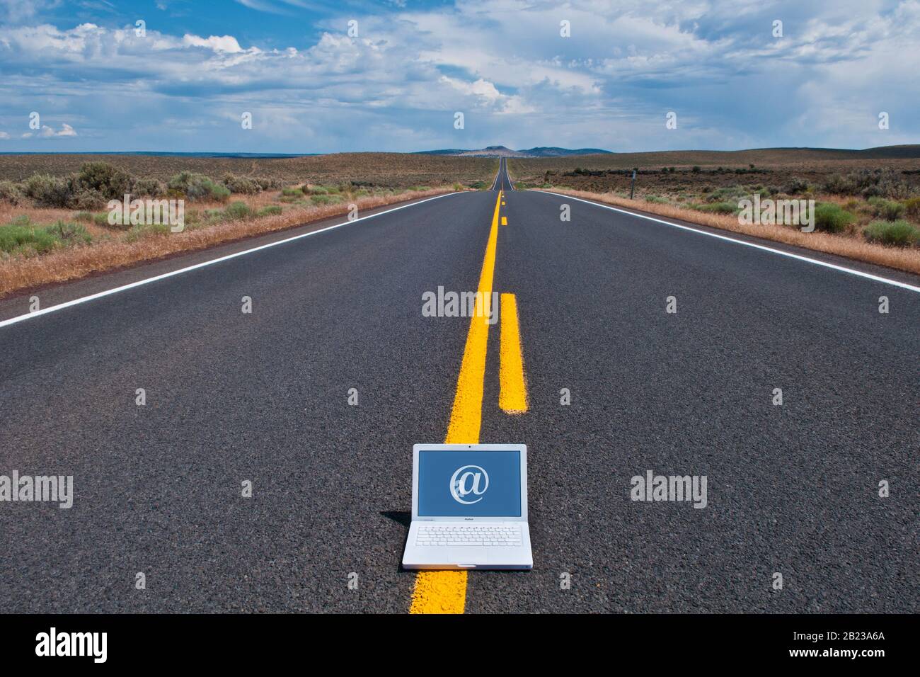 Abstract Information highway with computer in middle of deserted road ...
