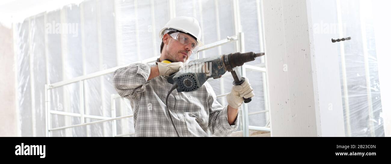 man using an electric pneumatic drill making a hole in wall ...