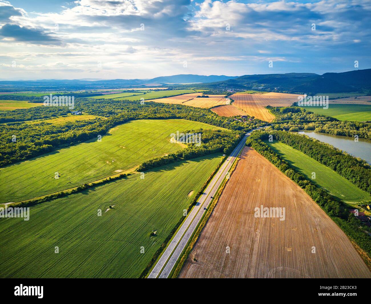 Summer landscape with fields, meadows, lake and mountains. Road on the ...