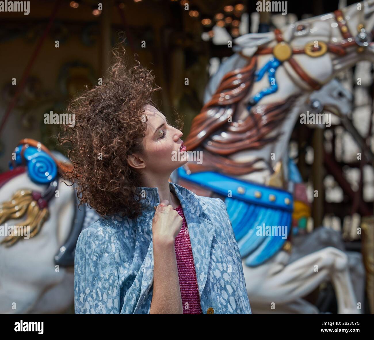 Young female model posing in front of a fairground carousel Stock Photo ...