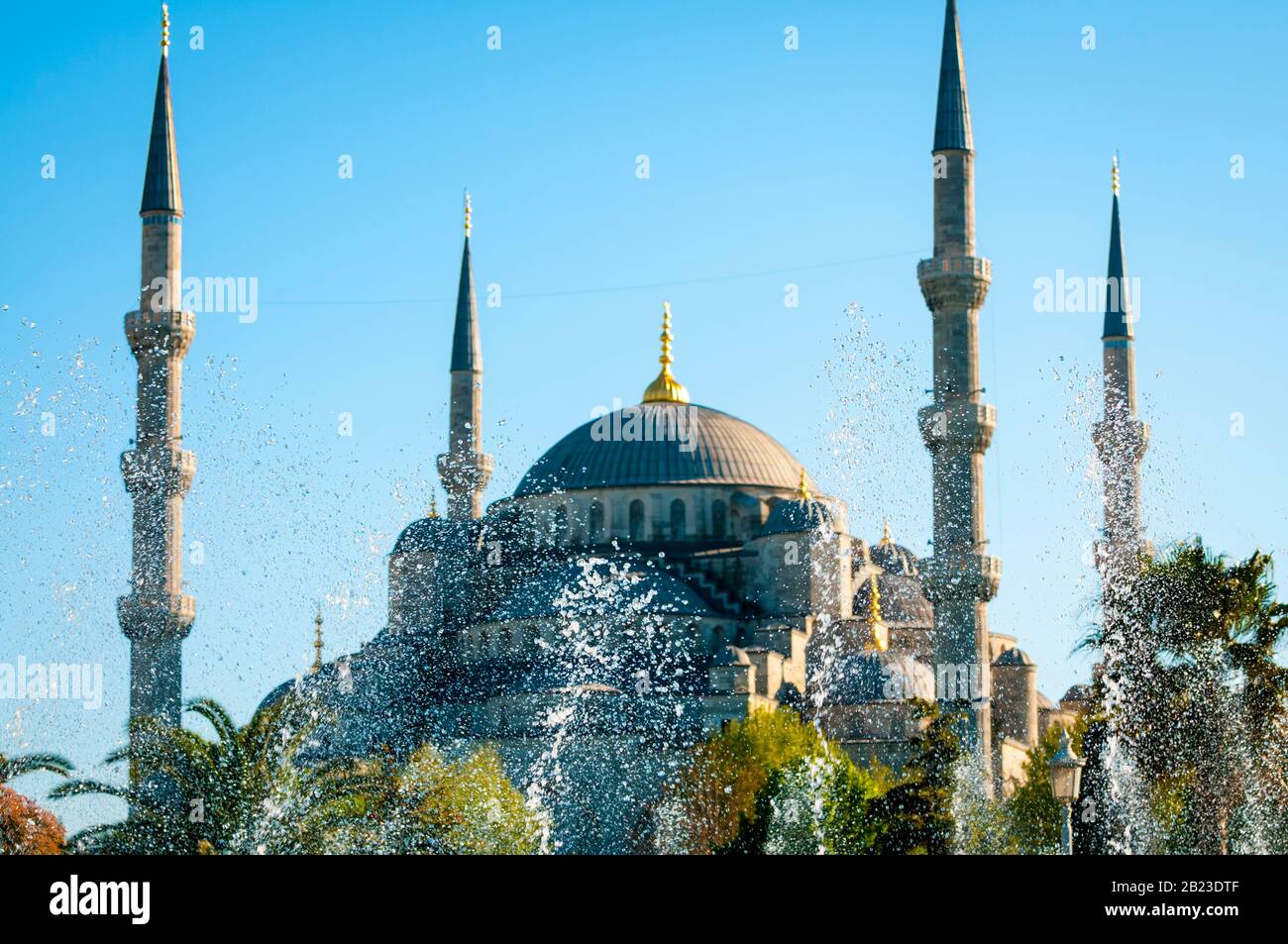 Sunny view of the dome and minarets of the Blue Mosque through fountain ...