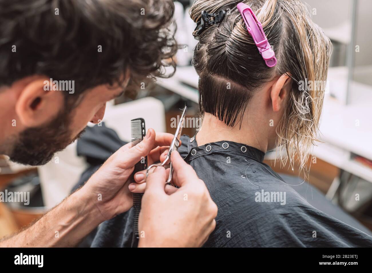 Master hairdresser cuts hair of blond woman in salon. Close up photo ...