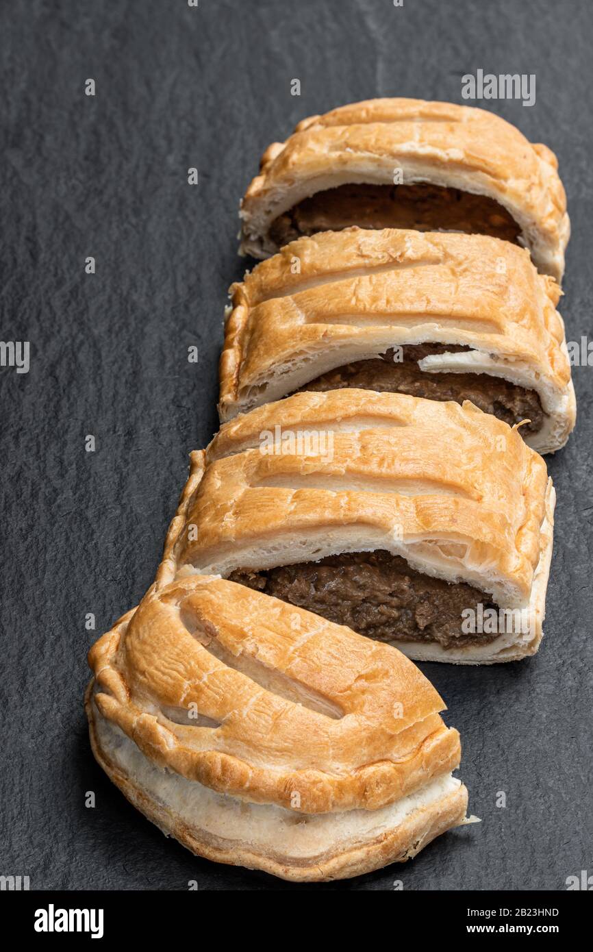 Homemade flaky pasty with mince meat filling on black stone background ...