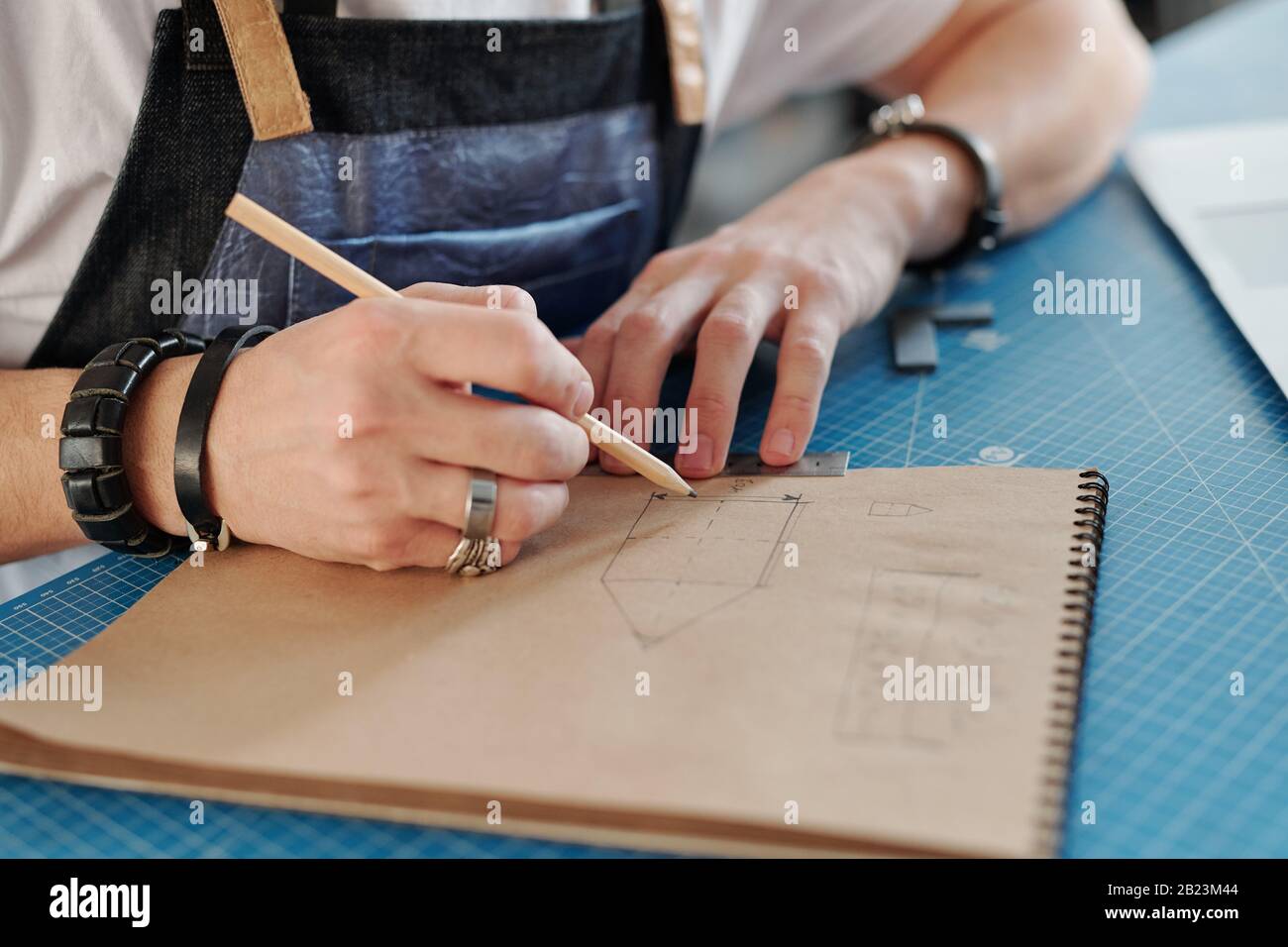 Hand of young craftsman with pencil over page of notepad while drawing ...