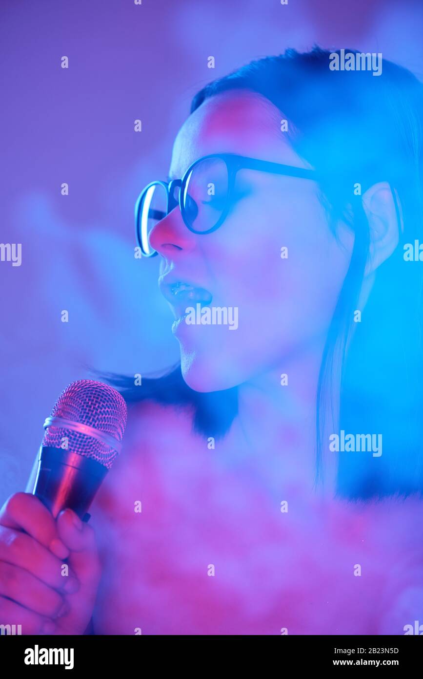 Pretty young emotional female singer with microphone by mouth ...