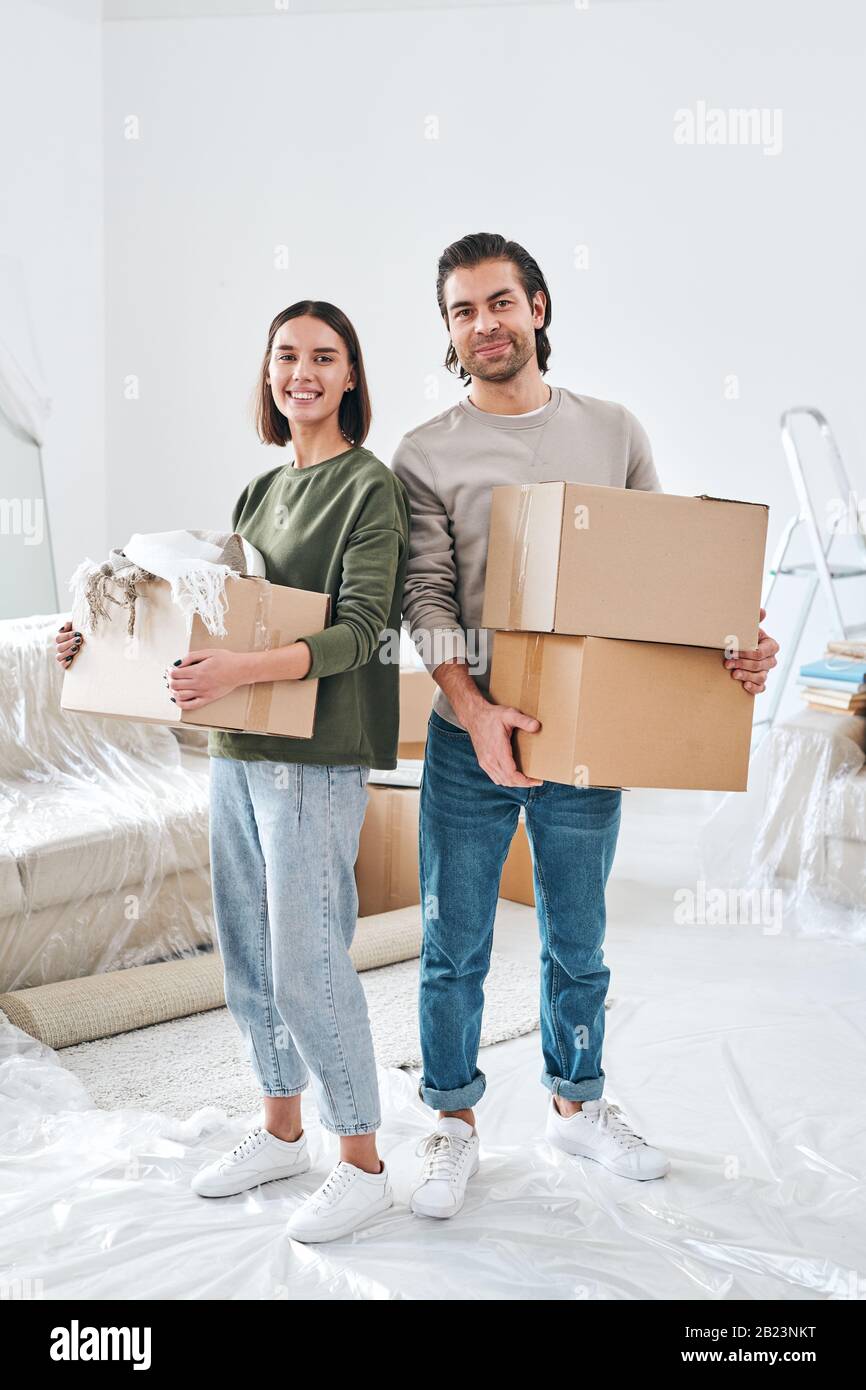 Cheerful young couple in casualwear holding carton boxes with packed ...