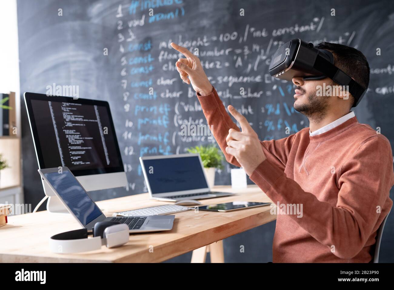 Young programmer in vr headset testing or presenting new software while ...