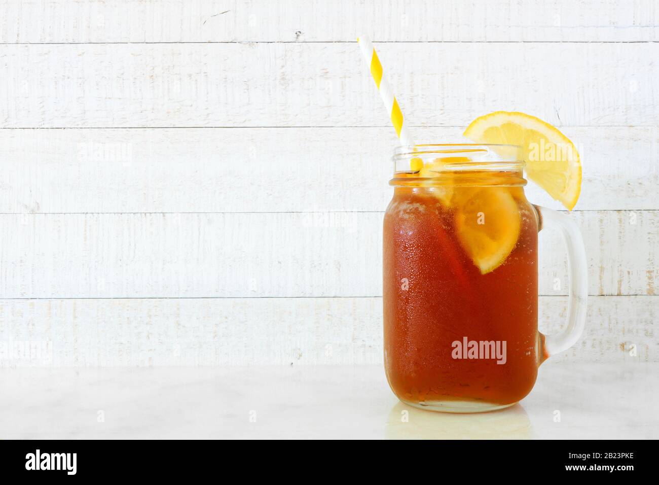 Summer iced tea in a mason jar glass. Side view on a white wood ...