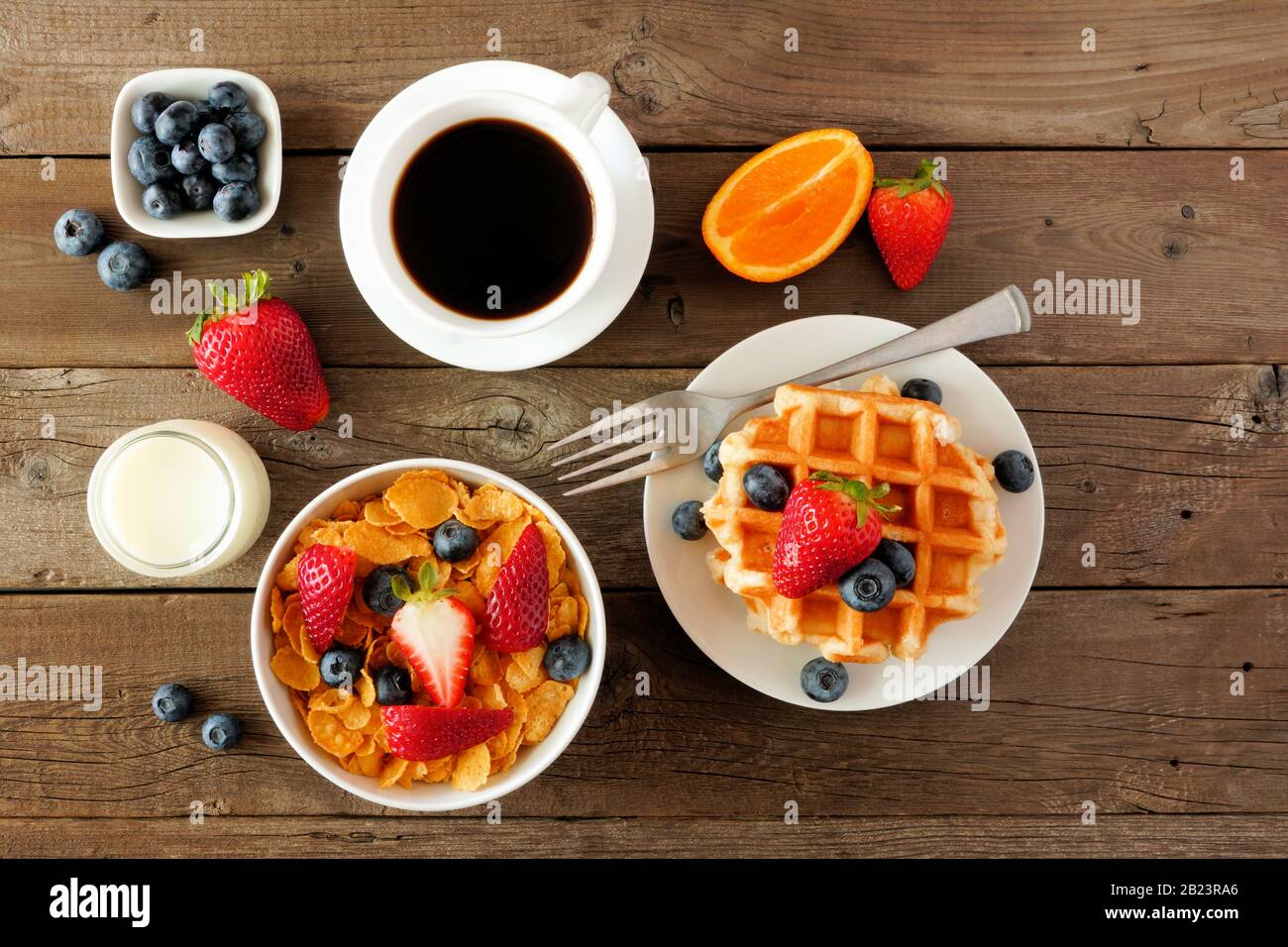 Breakfast food table scene. Fruits, cereal, waffles, milk and coffee ...