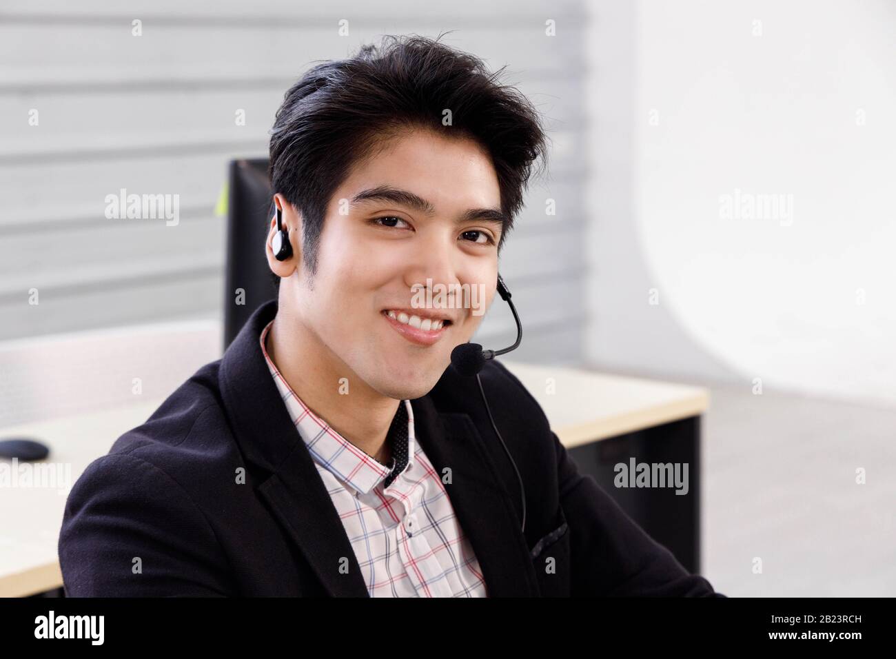 Portrait of handsome Asian male call center operator wear headphones ...