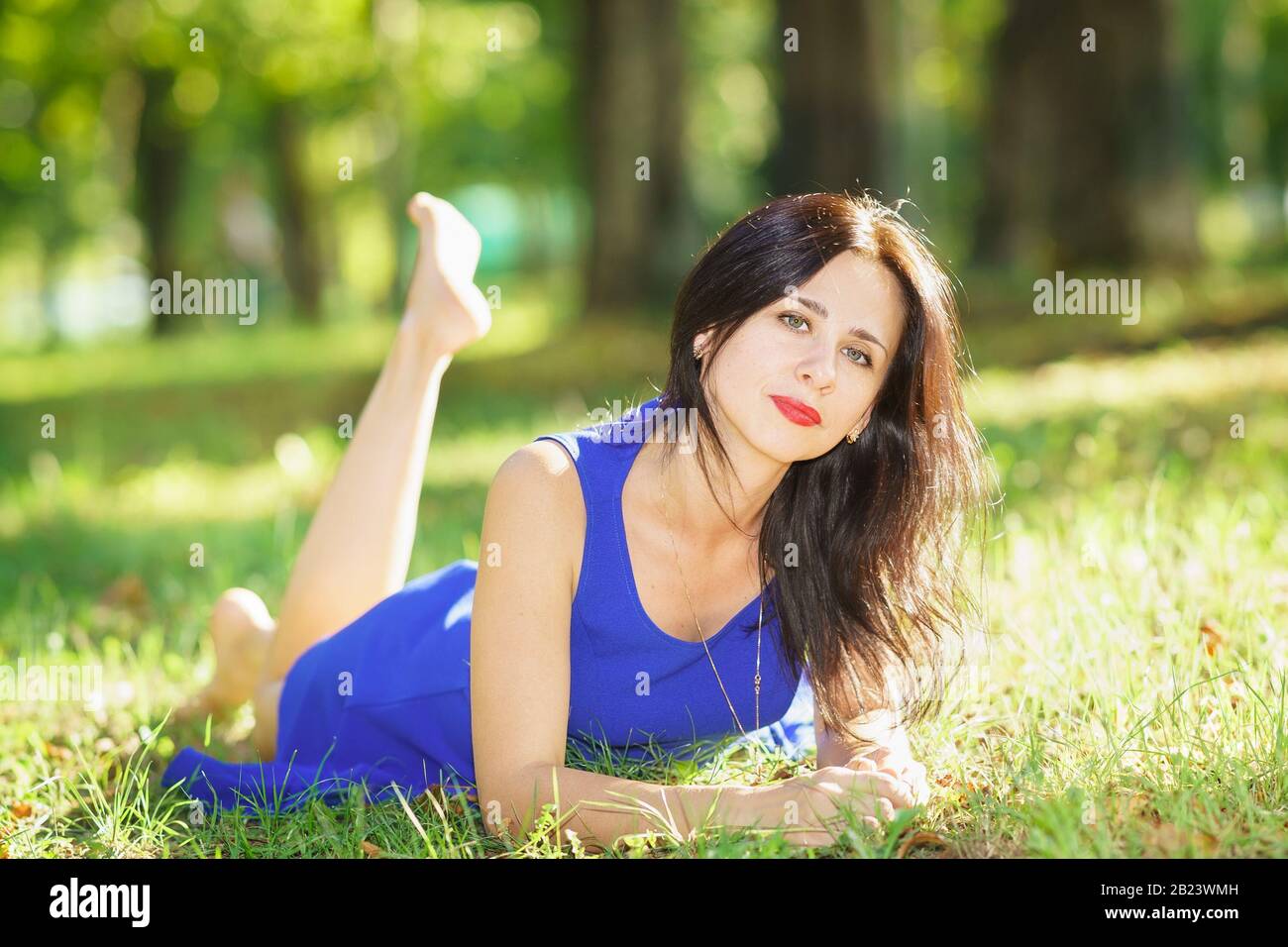 Beautiful Young Woman In Blue Dress Lying On The Grass Good Mood Stock