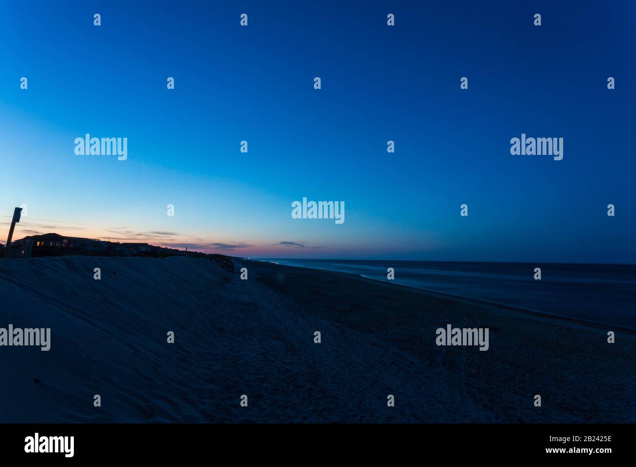 Blue night sky and beach landscape at night, with last rays of distant ...