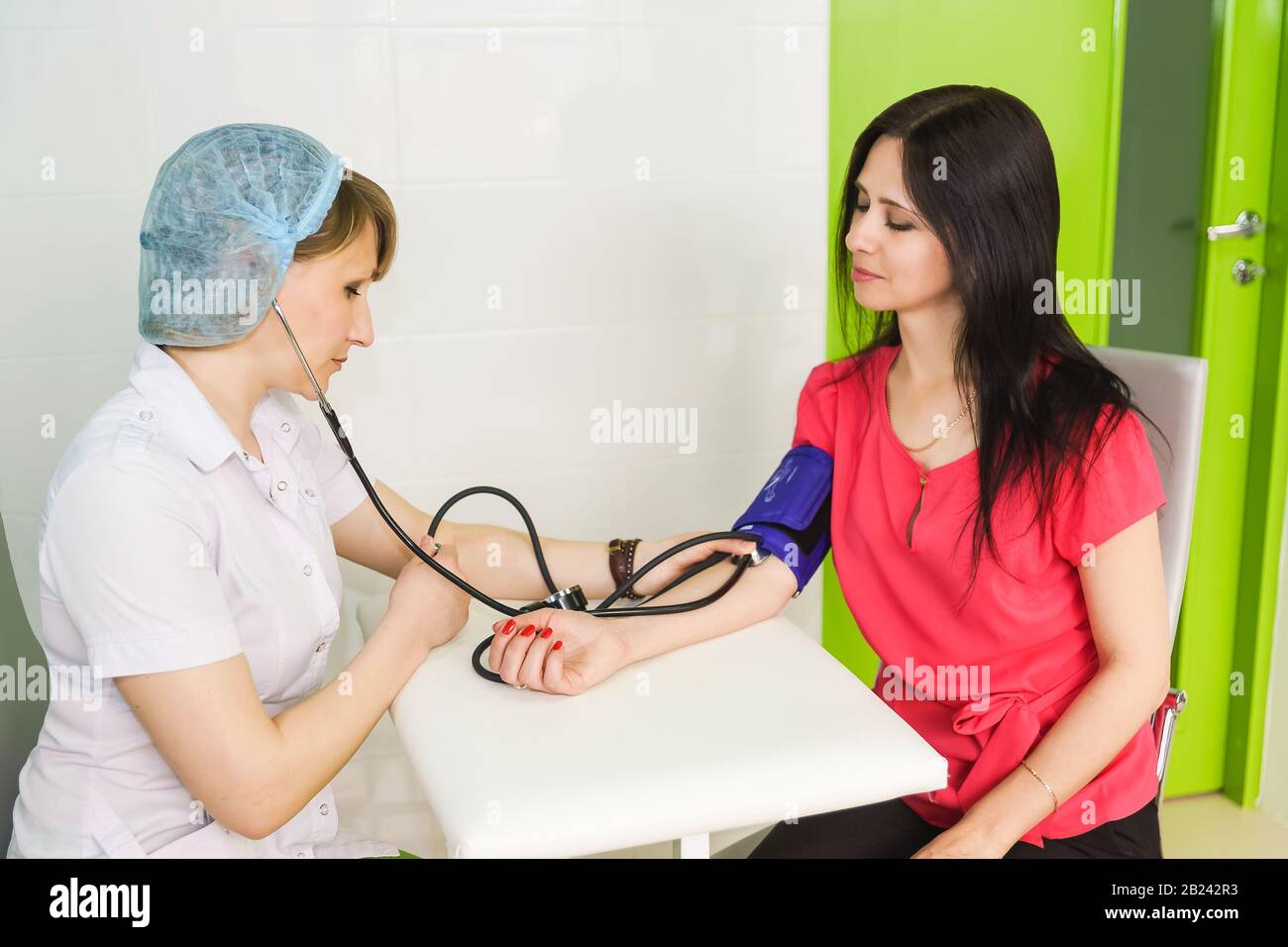 Nurse measuring the blood pressure the pressure the young woman ...