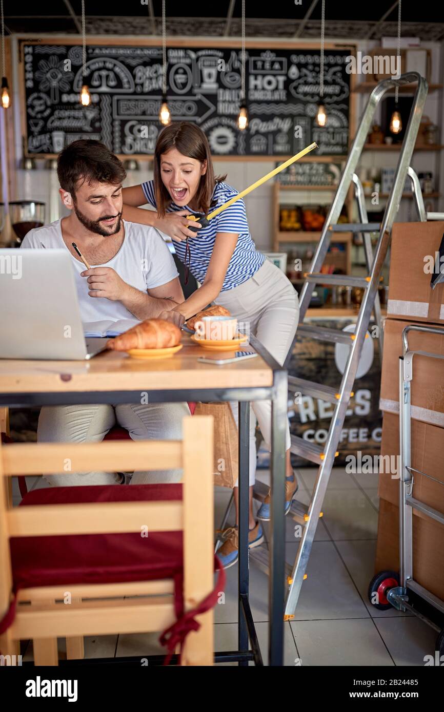 Business couple have fun as they prepare to open their cafe together ...