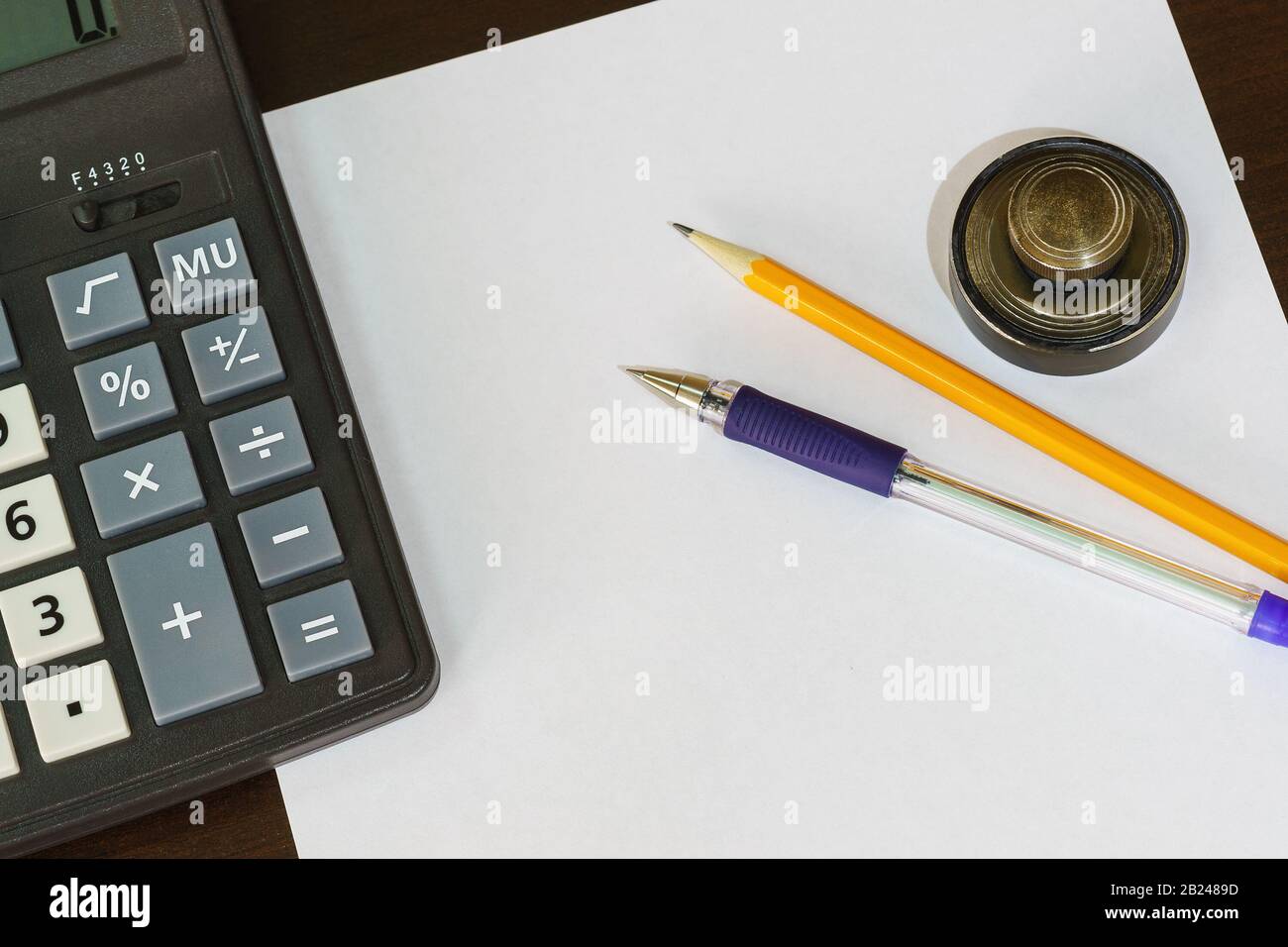 Calculator, print, pen and pencil lying on a blank sheet of paper. The ...