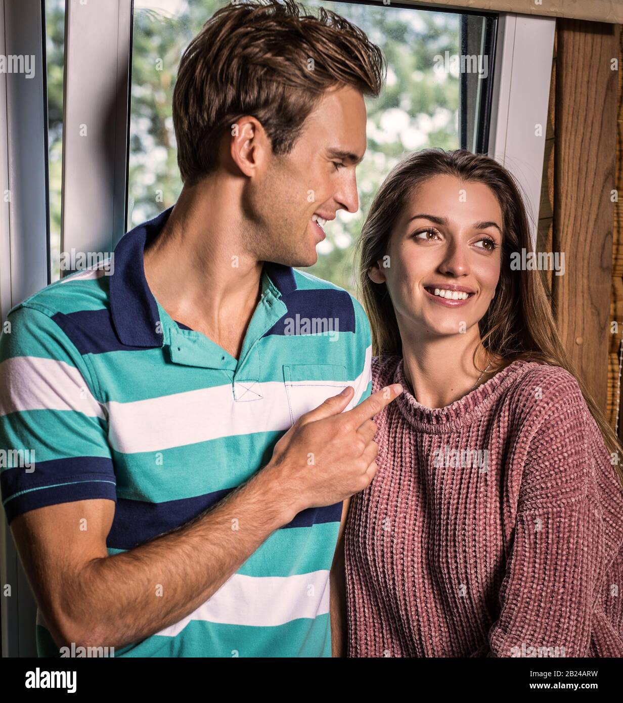 Young and beautiful happy family together in modern wooden house ...