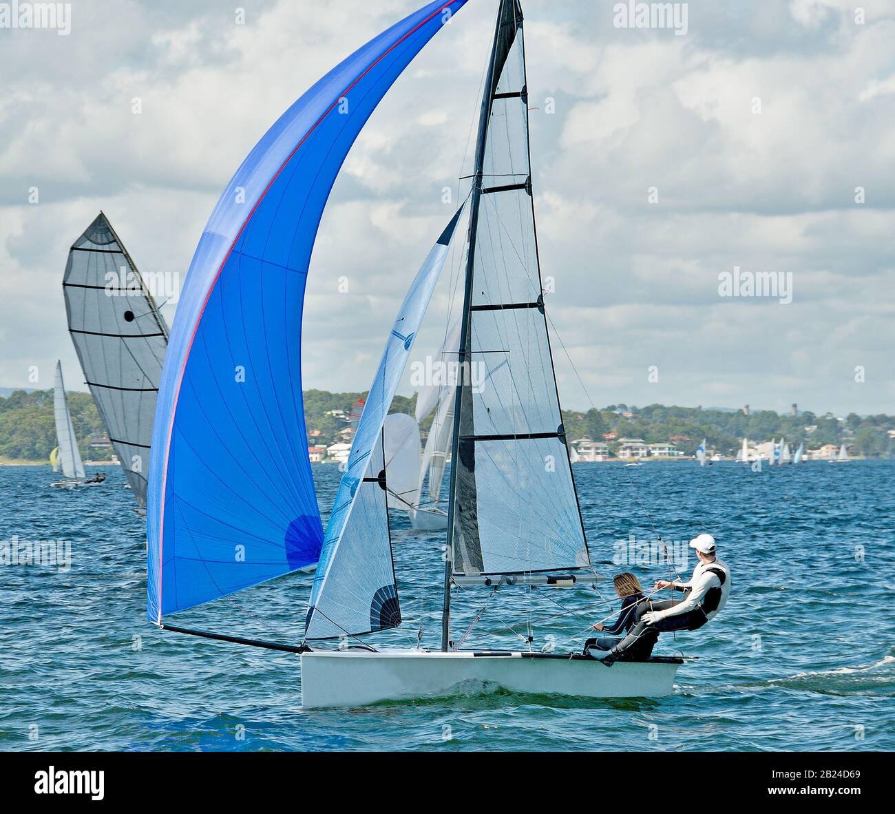 Children sailing / racing small sailboat with a blue spinnaker on a ...