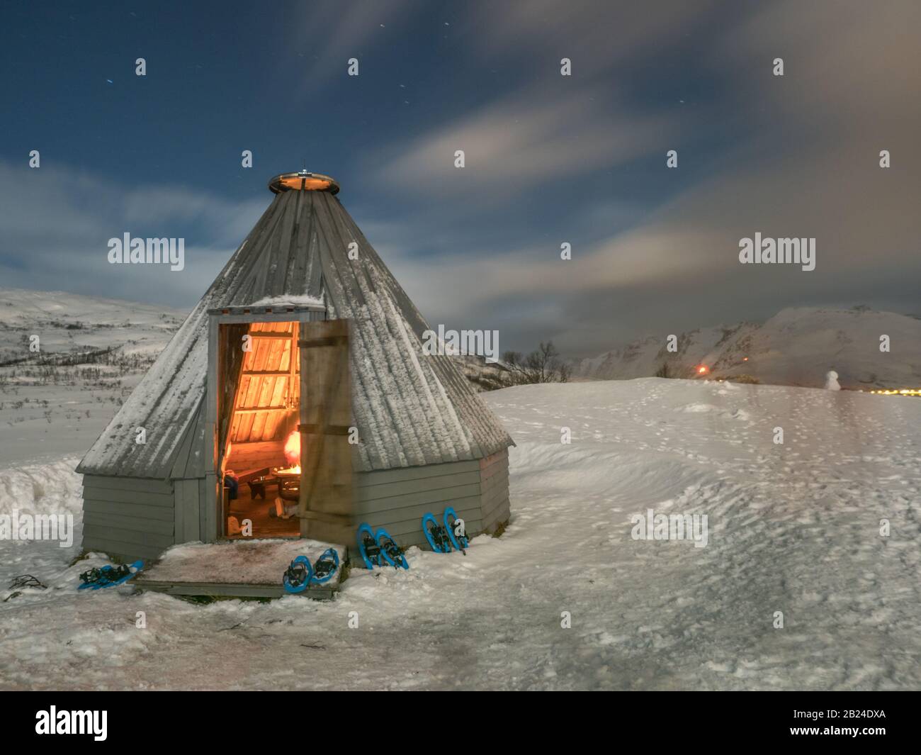 Wooden cabin in Northern Norway in winter. Visible bonfire burning ...