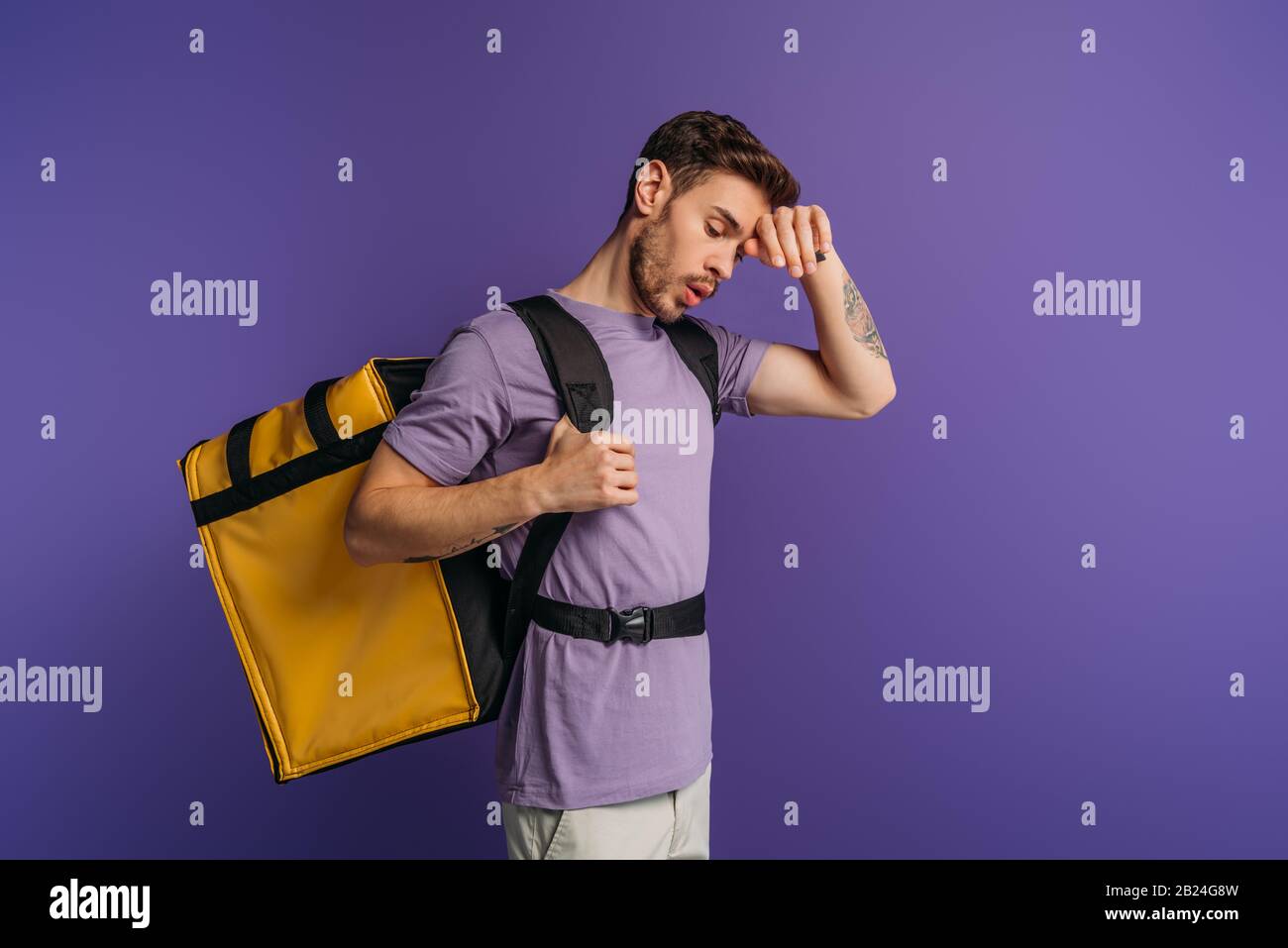 exhausted delivery man touching forehead while carrying thermo backpack ...