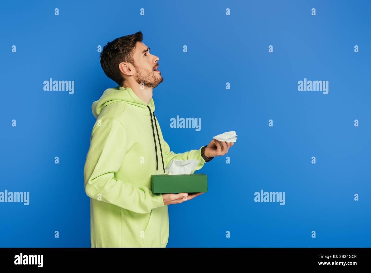 side view of sad man looking up and crying while holding paper napkin ...