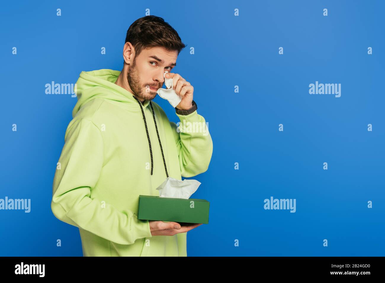 upset young man crying and wiping tears with paper napkin isolated on ...