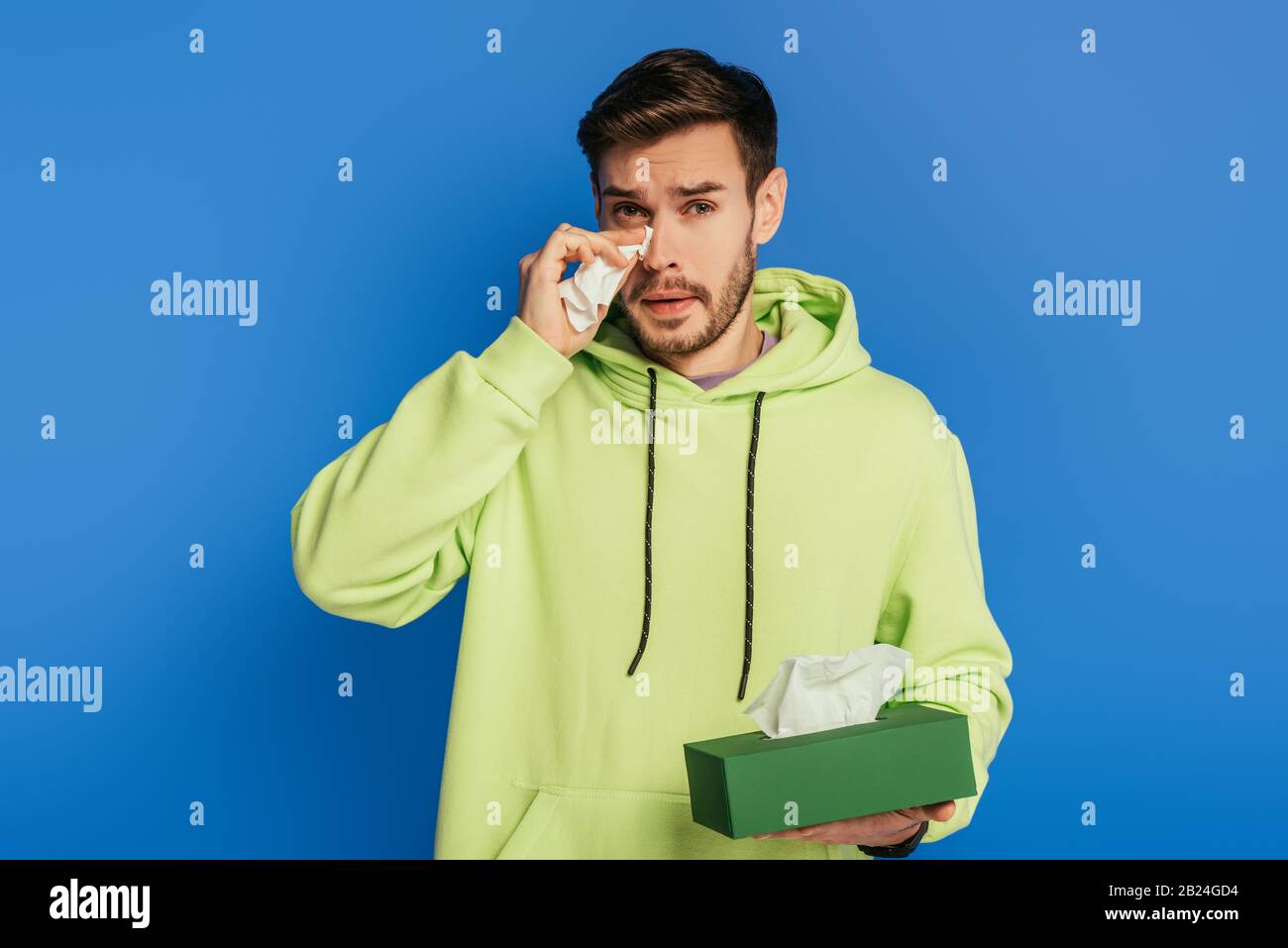 upset young man crying and wiping tears with paper napkin isolated on ...