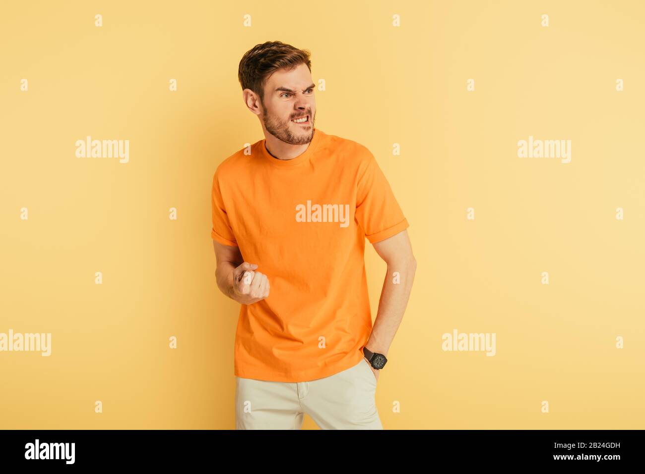 angry man grimacing and showing threatening gesture while looking away ...