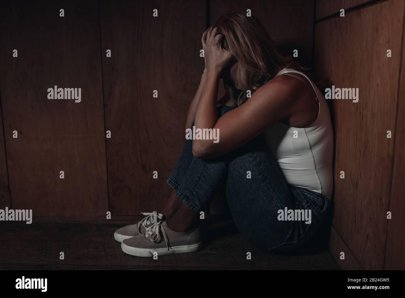 Side view of victim putting head on hands, sitting in corner Stock ...