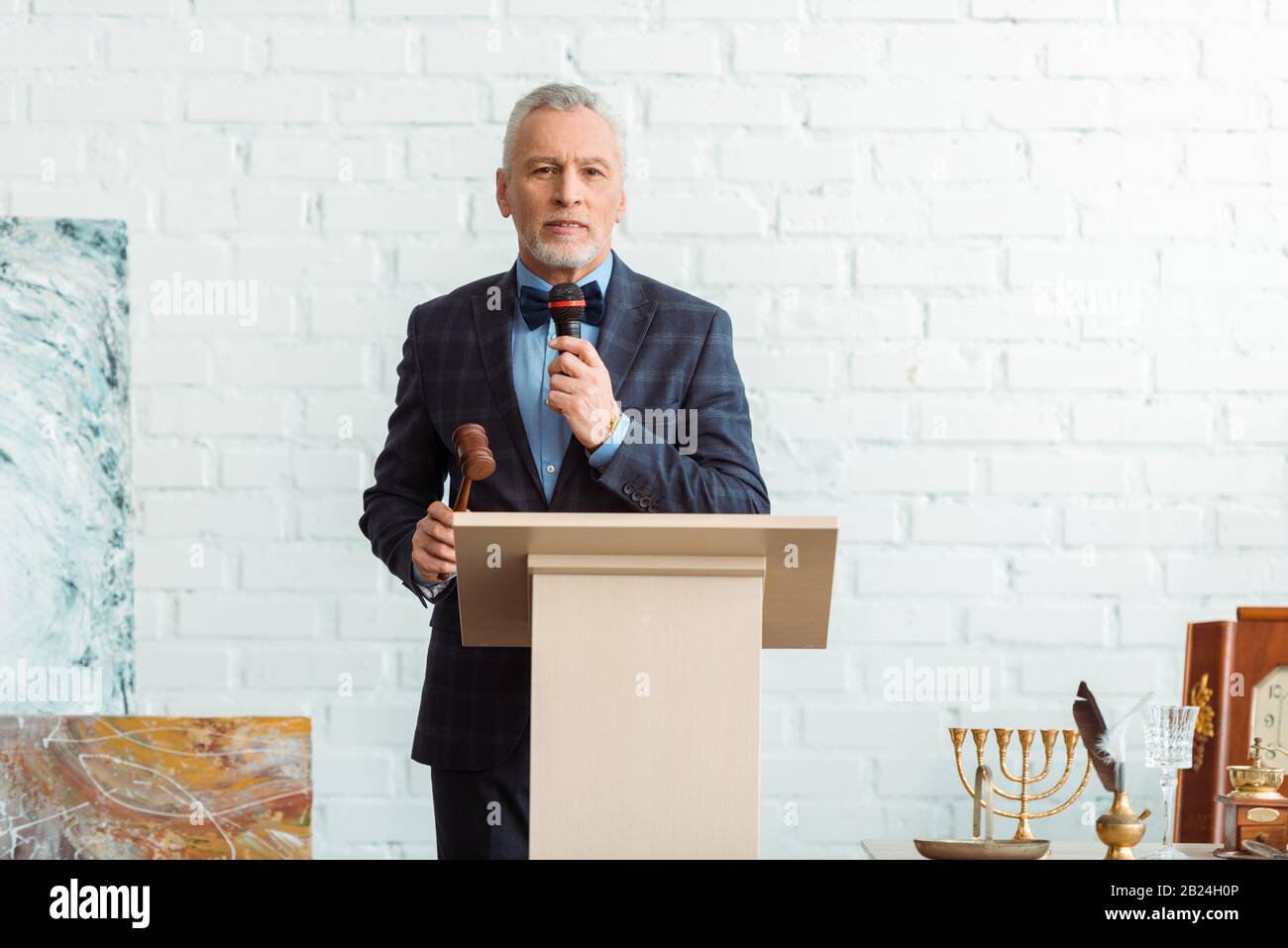 auctioneer talking with microphone and holding gavel during auction ...